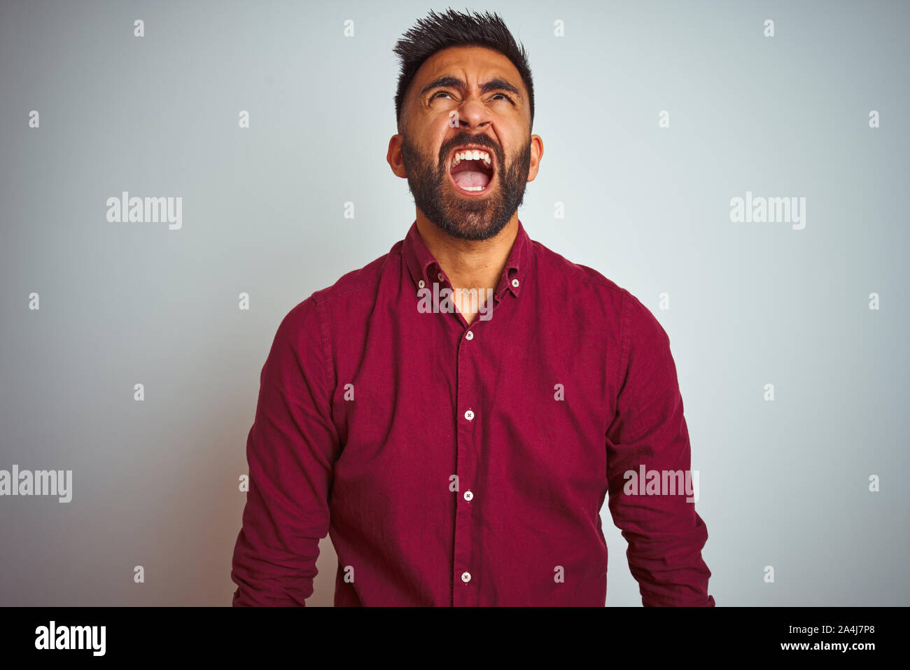 Young indian man wearing red elegant shirt standing over isolated grey ...