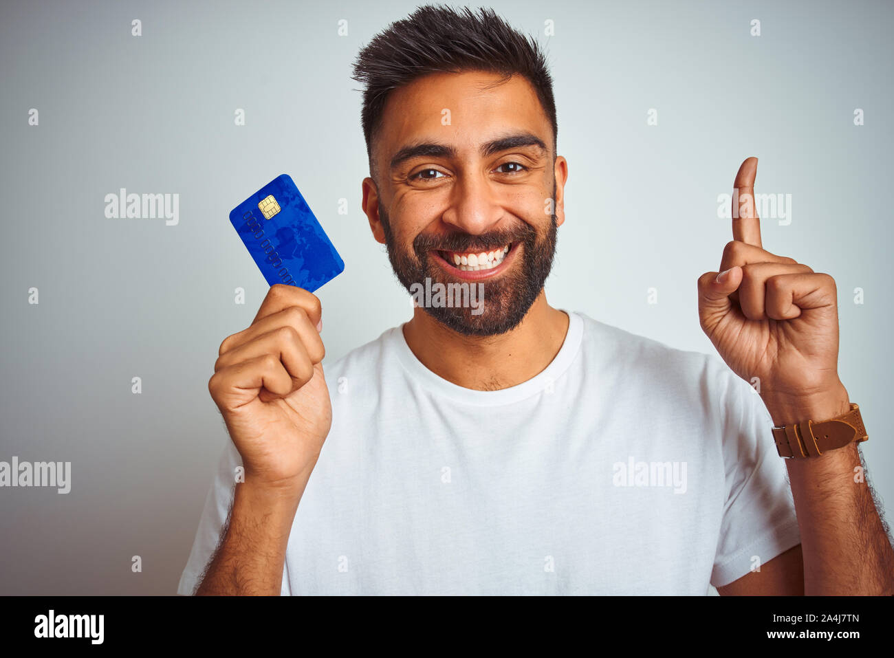 Young indian customer man holding credit card standing over isolated ...
