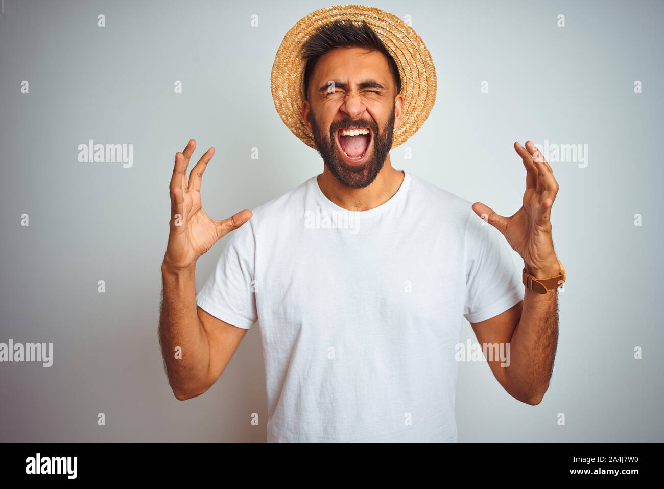 Young indian man on holiday wearing summer hat standing over isolated ...