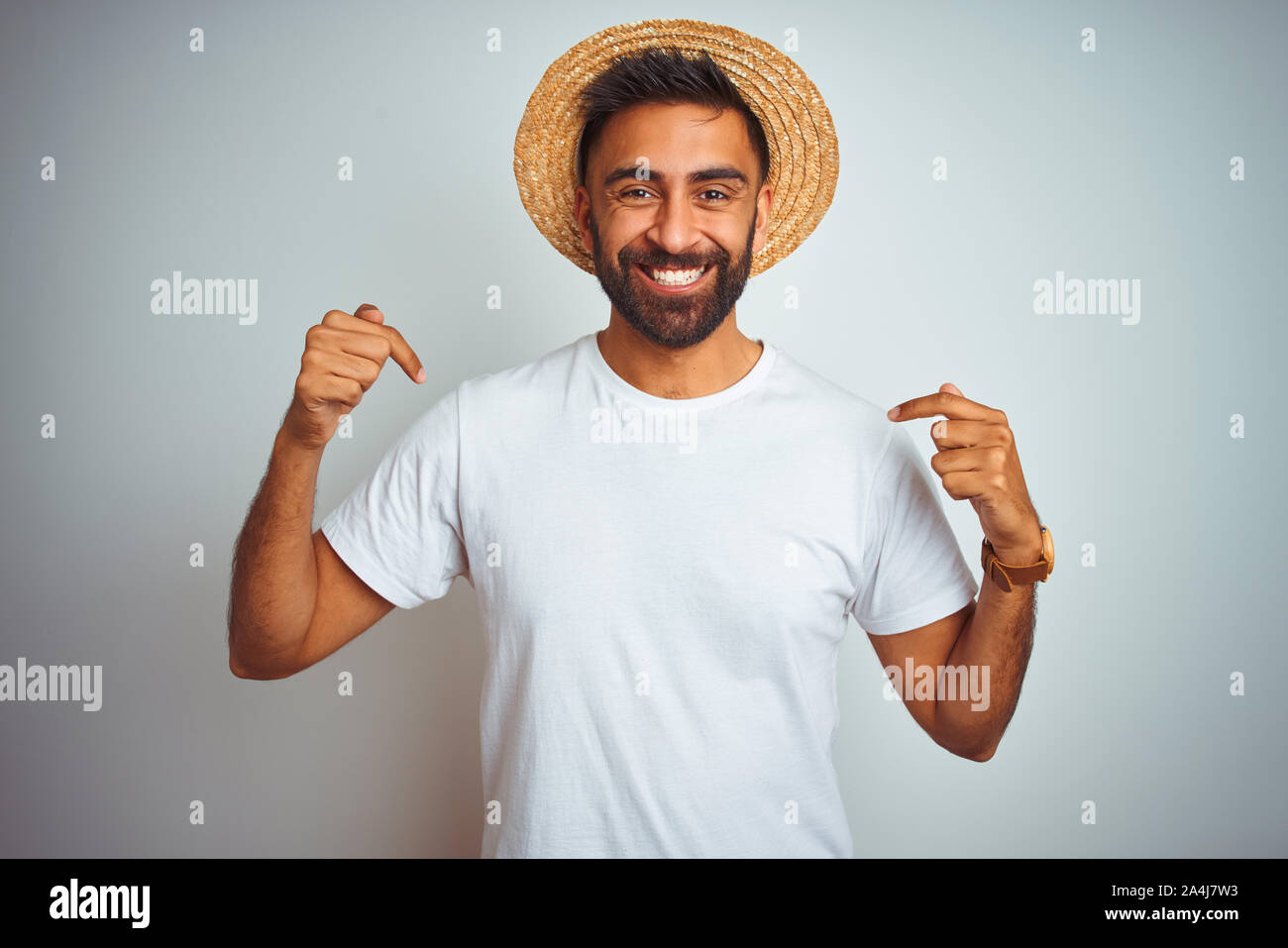 Young indian man on holiday wearing summer hat standing over isolated ...