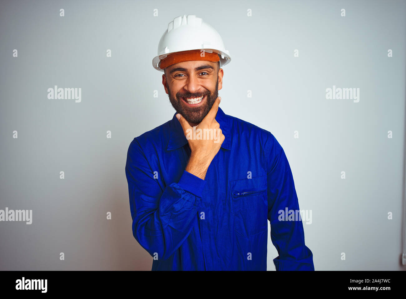 Handsome indian worker man wearing uniform and helmet over isolated ...