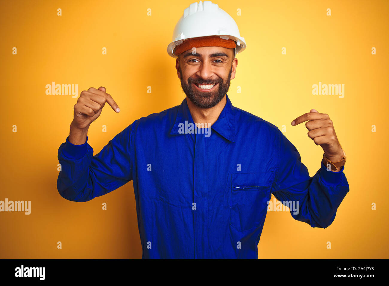 Handsome indian worker man wearing uniform and helmet over isolated ...