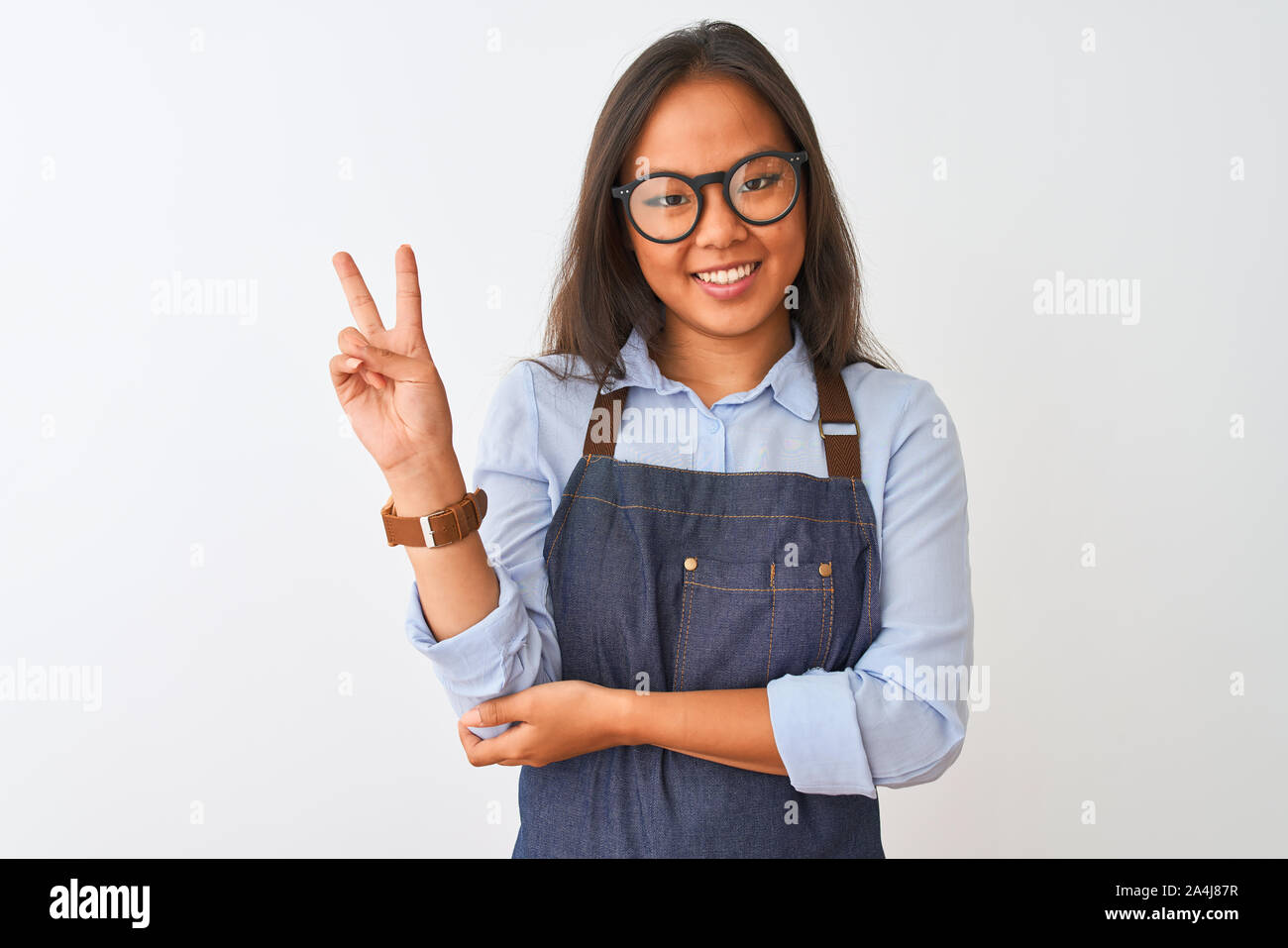 Young beautiful chinese woman wearing glasses and apron over isolated ...