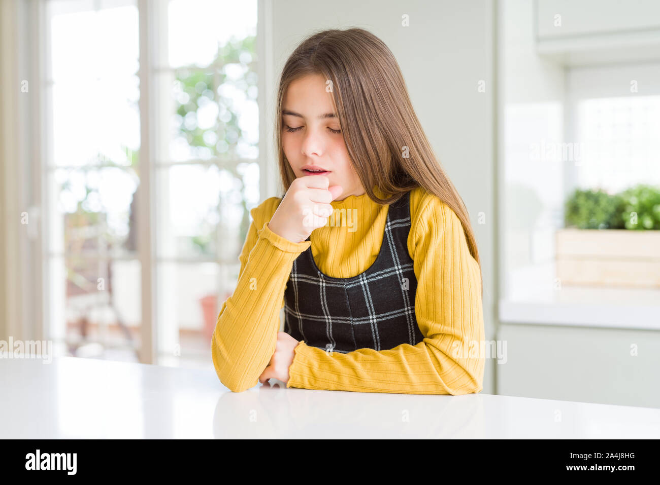 Young beautiful blonde kid girl wearing casual yellow sweater at home ...