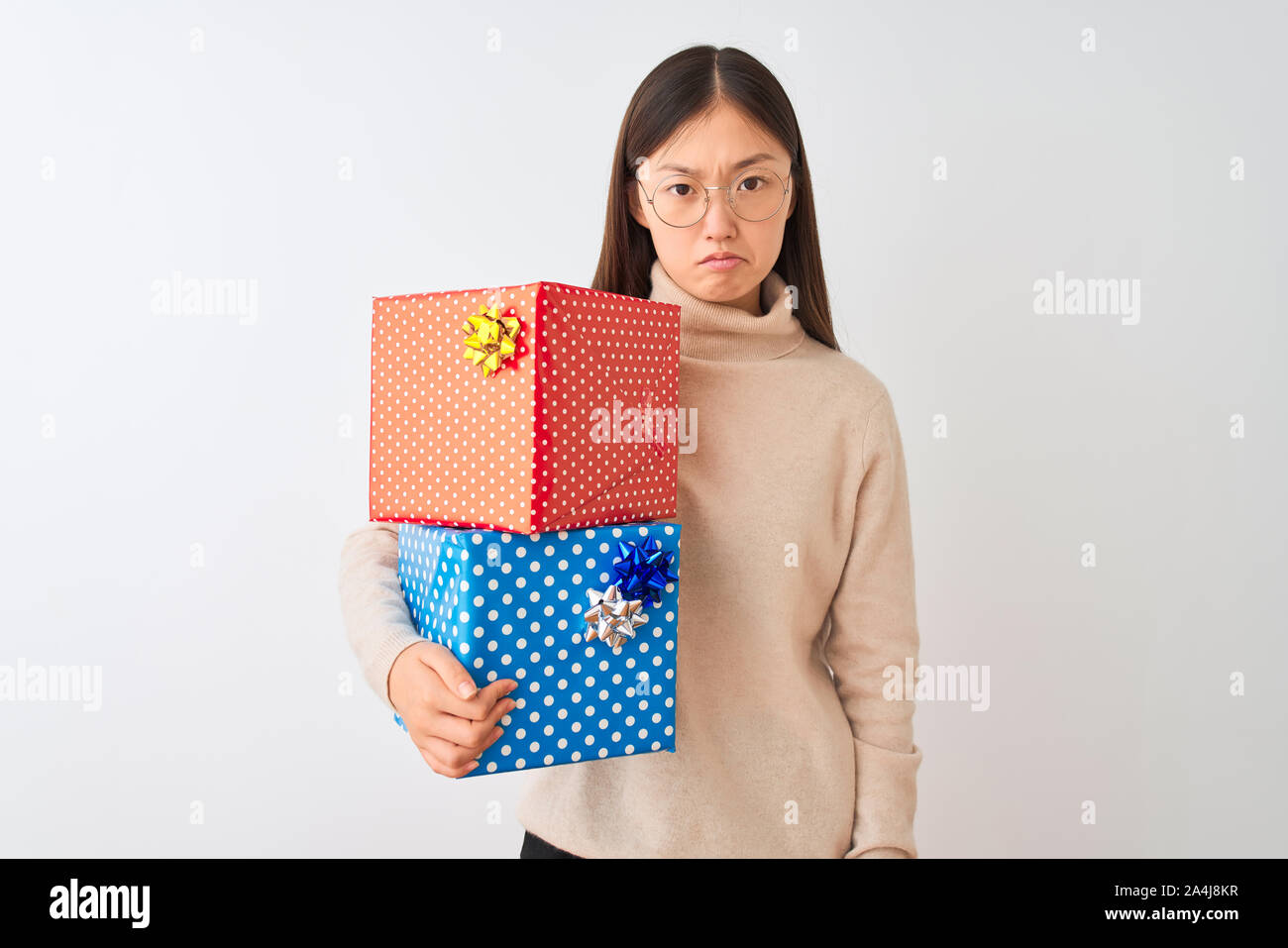 Young chinese woman holding birthday gifts over isolated white ...