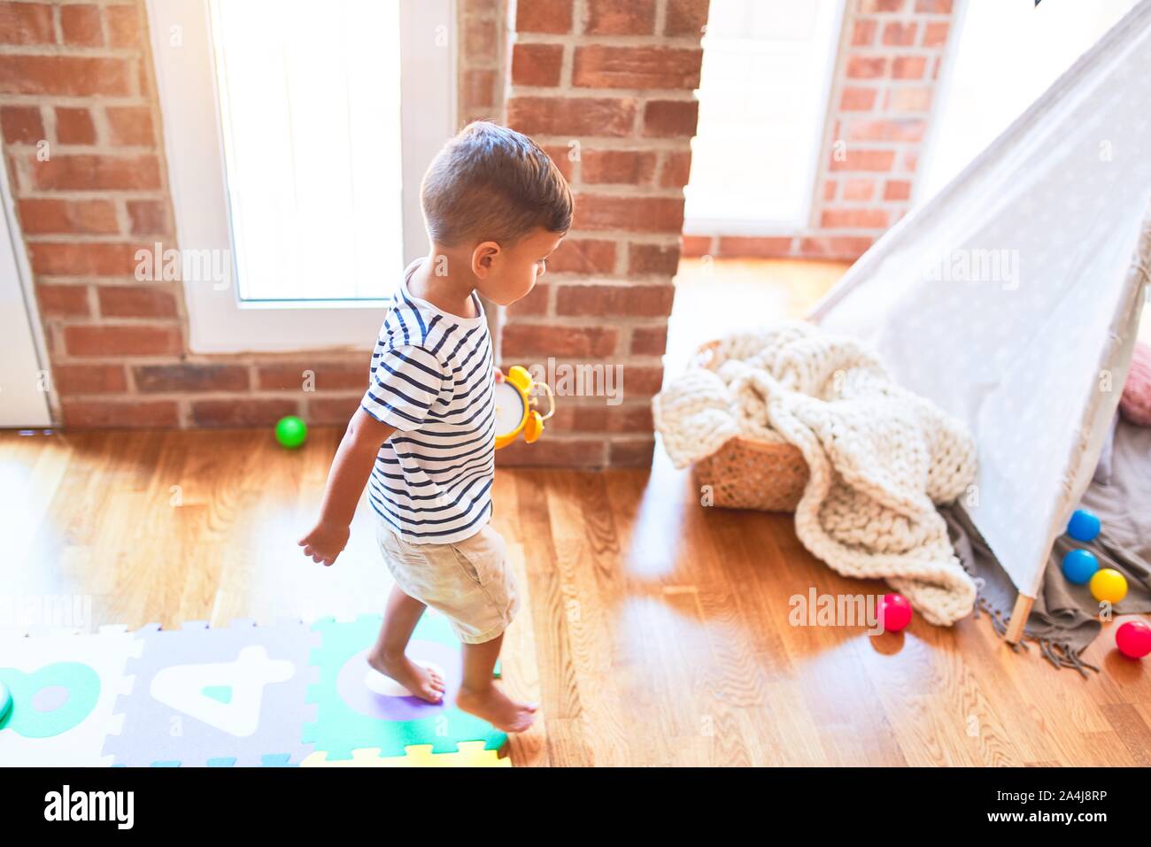 Beautiful toddler boy standing at kindergarten with lots of toys Stock ...