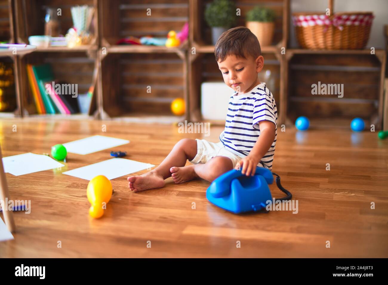 Beautiful toddler boy playing with vintage blue phone at kindergarten ...