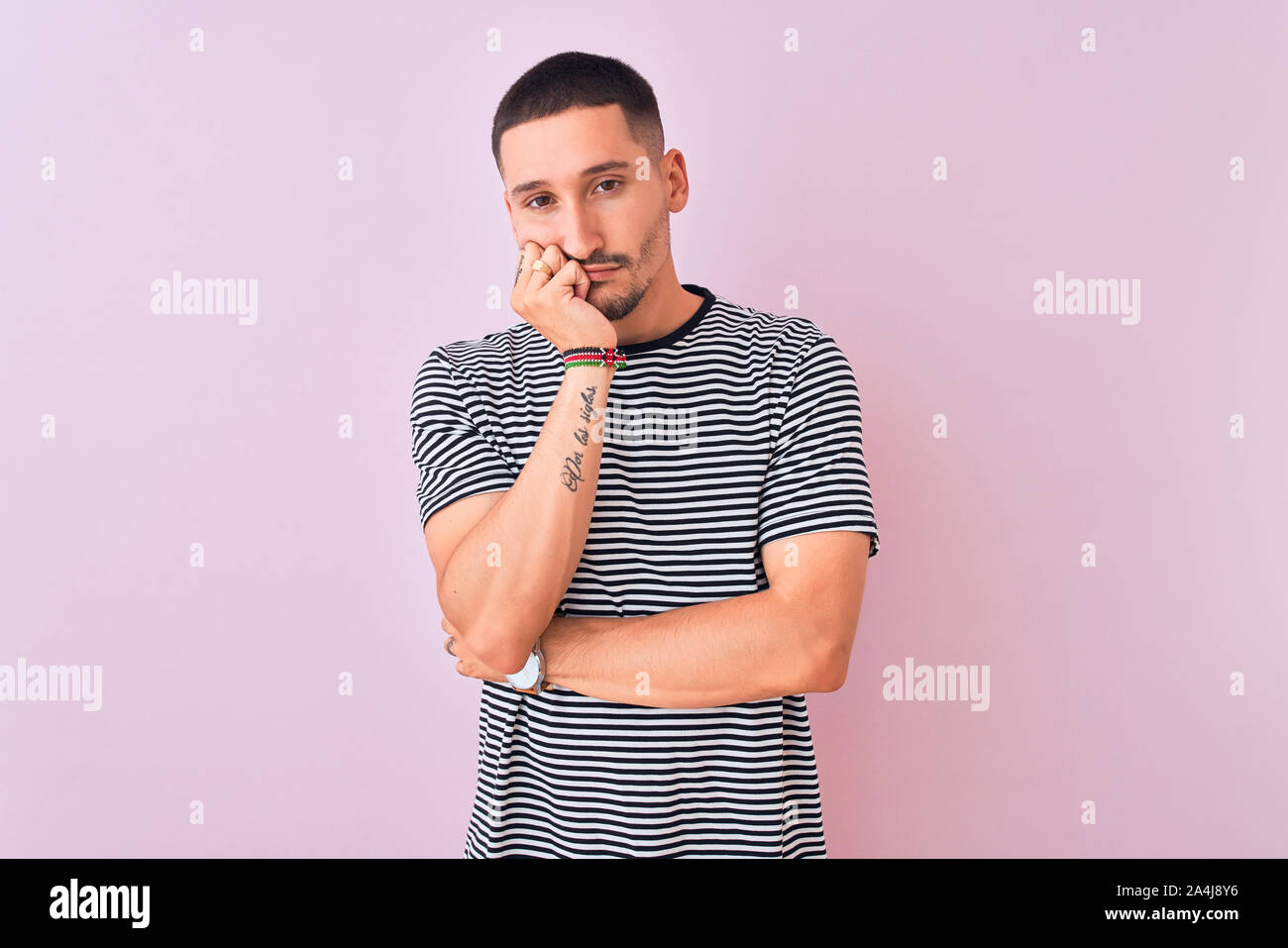 Young handsome man wearing striped t-shirt standing over pink isolated ...
