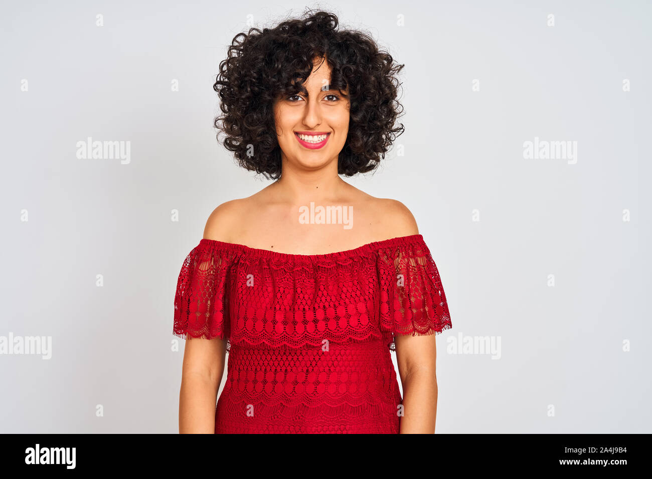 Young arab woman with curly hair wearing red dress standing over ...