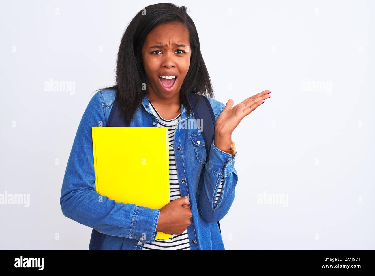 Young african american student woman wearing backpack and book over ...