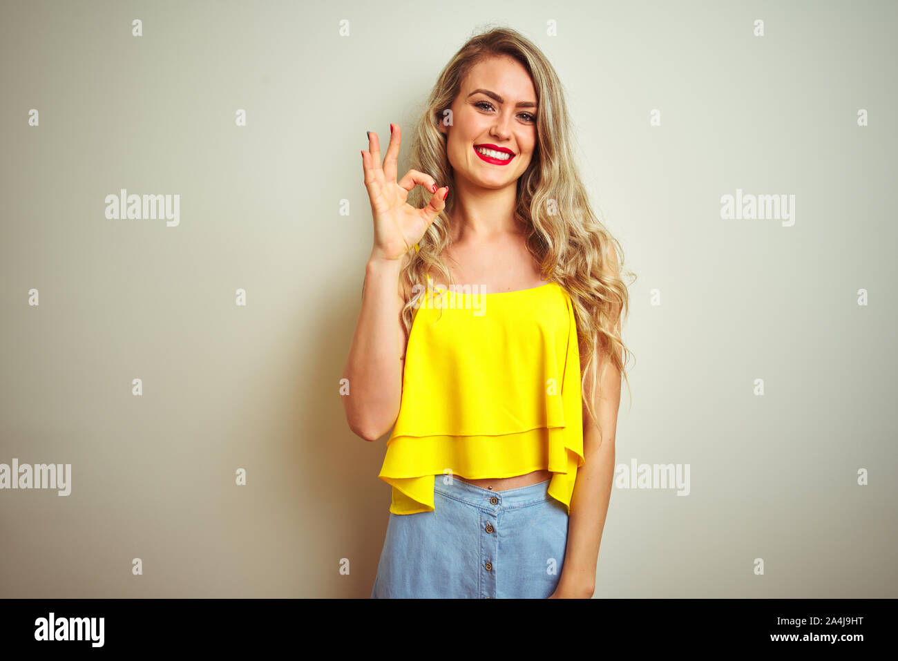 Young beautiful woman wearing yellow t-shirt standing over white ...
