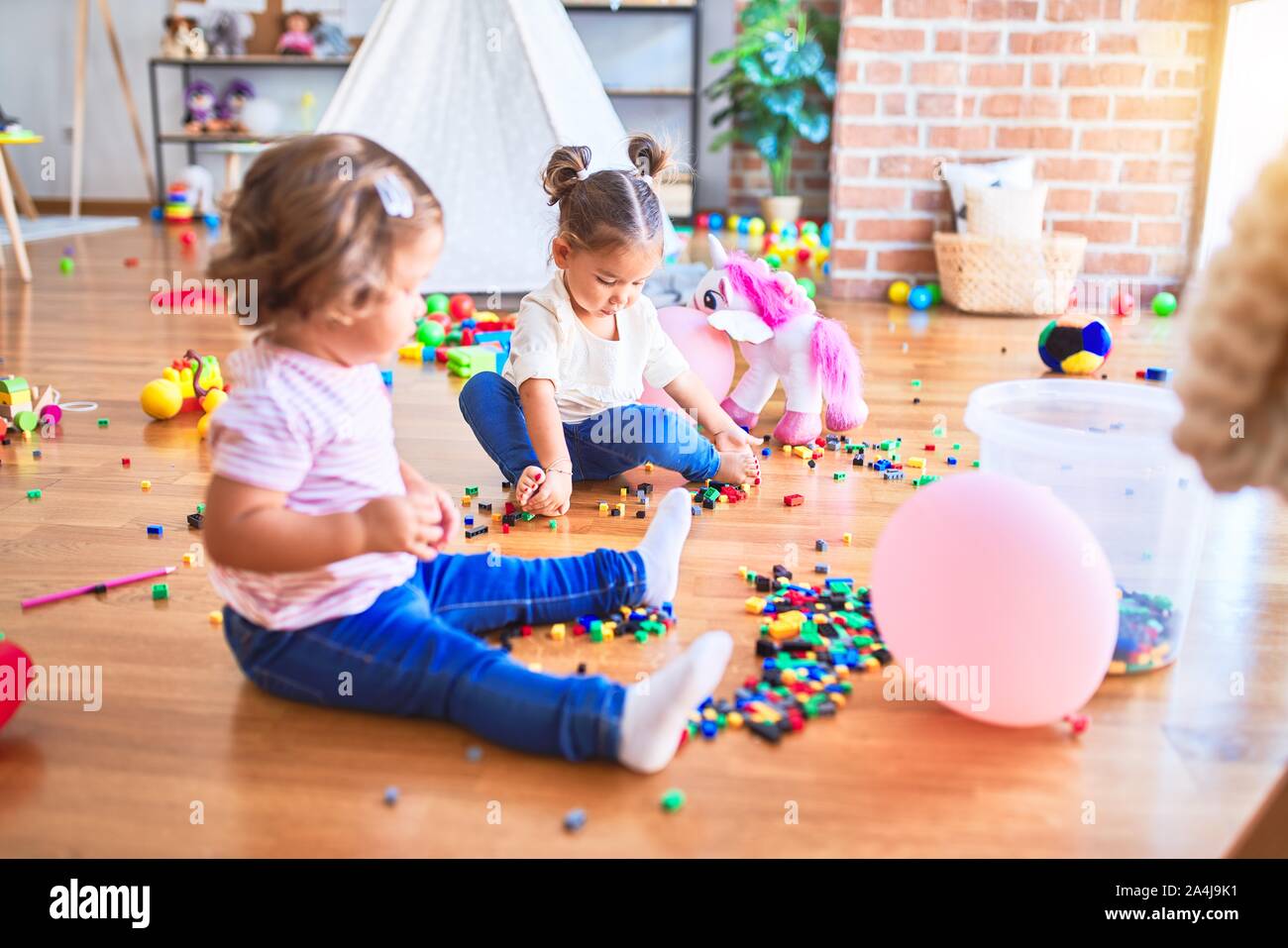 Adorable toddlers playing with building blocks toy at kindergarten ...