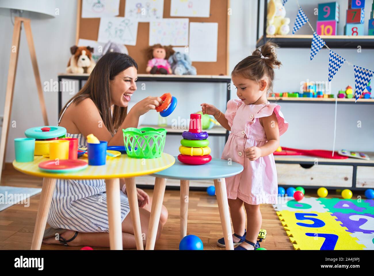 Young beautiful teacher and toddler building pyramid using hoops on the ...