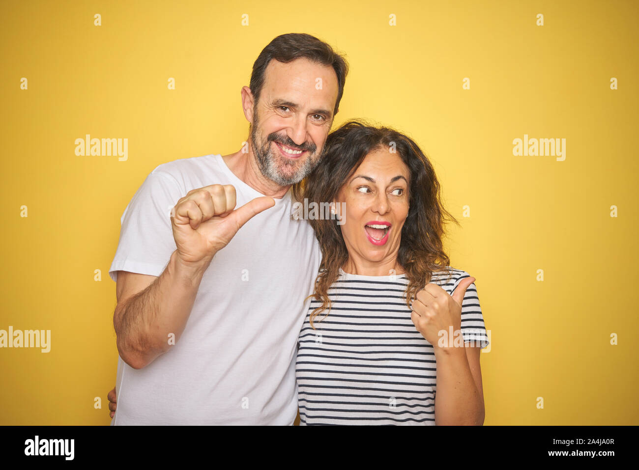 Beautiful middle age couple together standing over isolated yellow ...