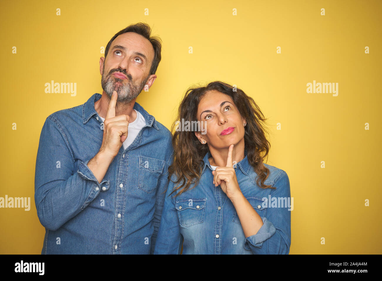 Beautiful middle age couple together standing over isolated yellow ...
