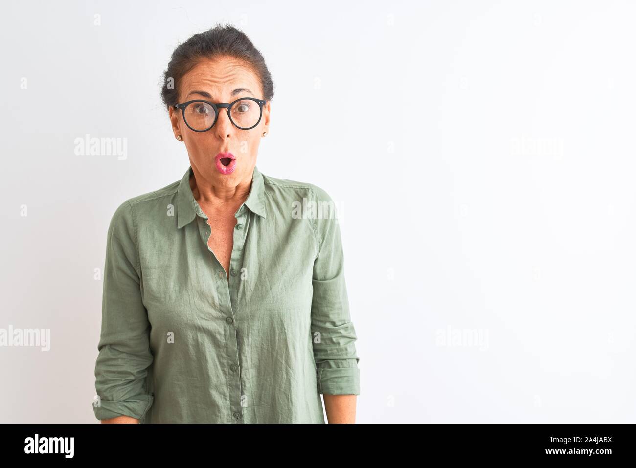 Middle age woman wearing green shirt and glasses standing over isolated ...