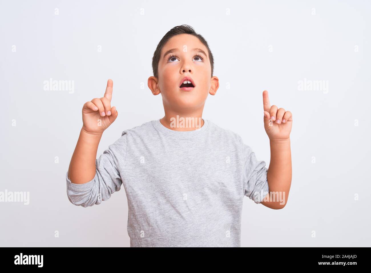 Beautiful kid boy wearing grey casual t-shirt standing over isolated ...