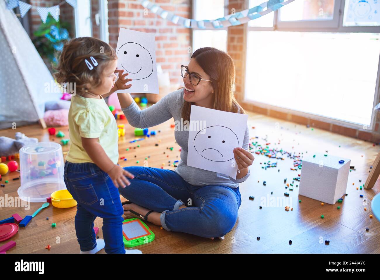 Young beautiful psicologist and toddler doing therapy using emoji ...