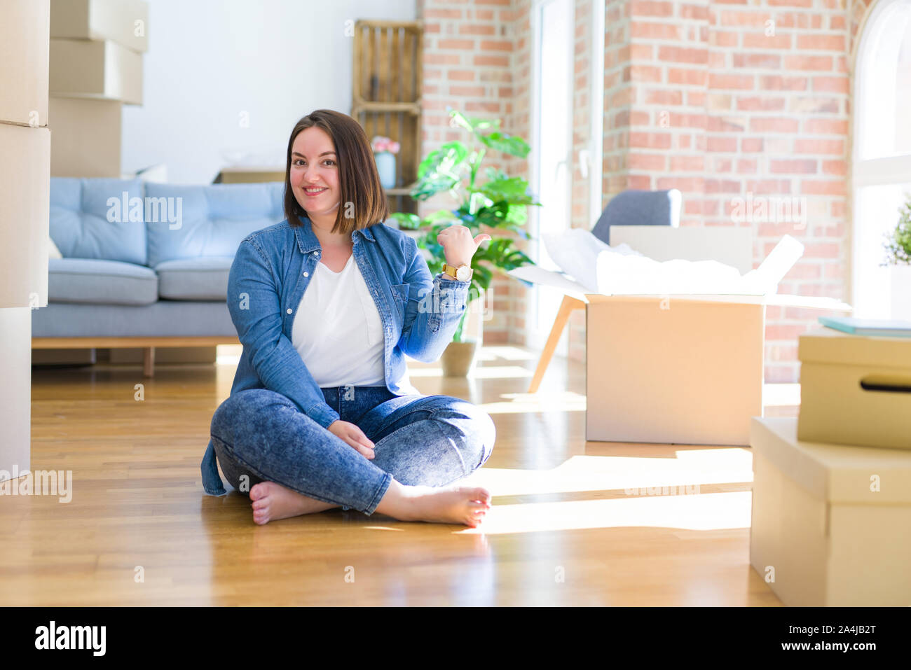 Young plus size woman sitting on the floor around cardboard boxes ...