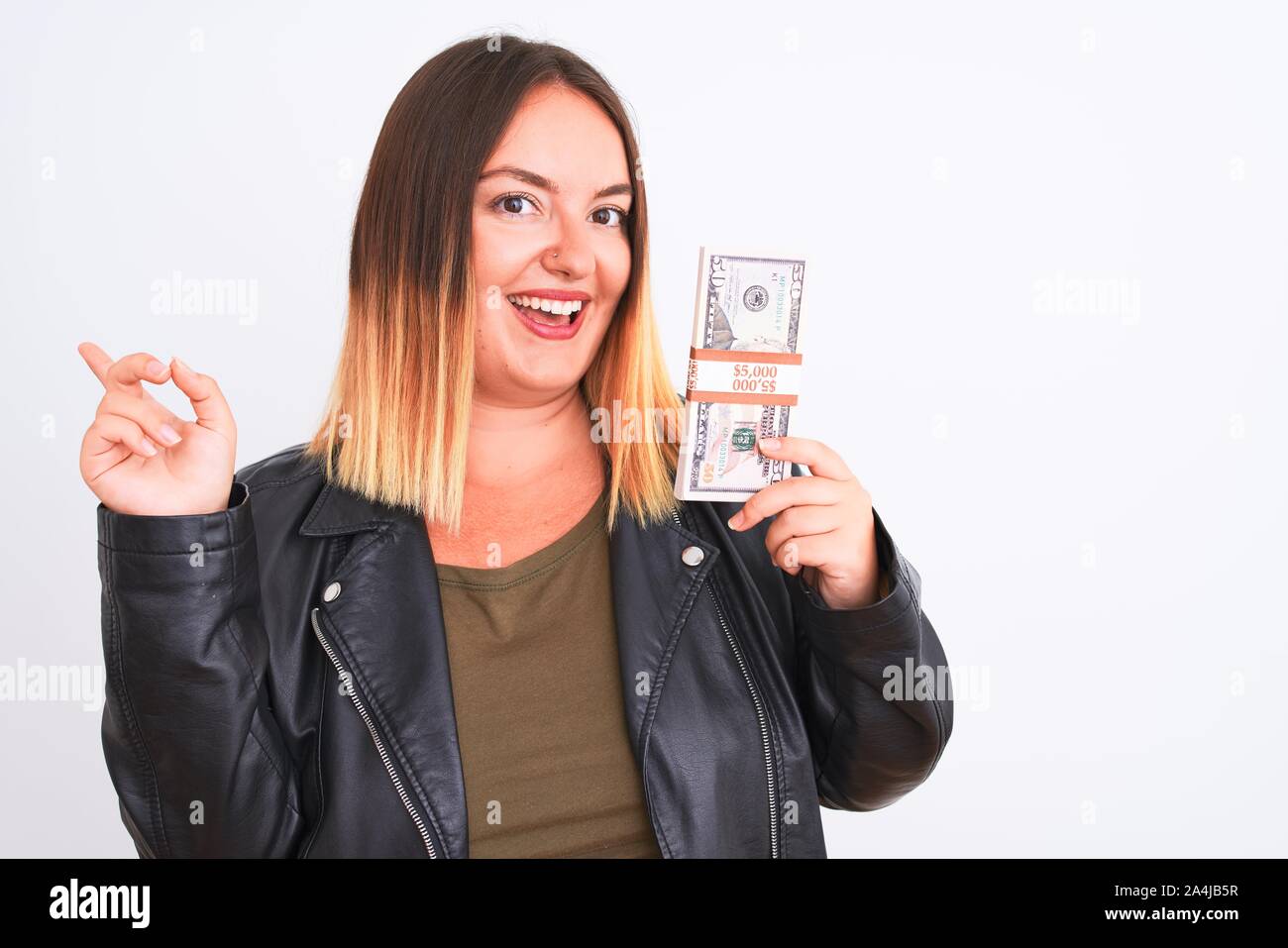 Young beautiful woman holding dollars standing over isolated white ...
