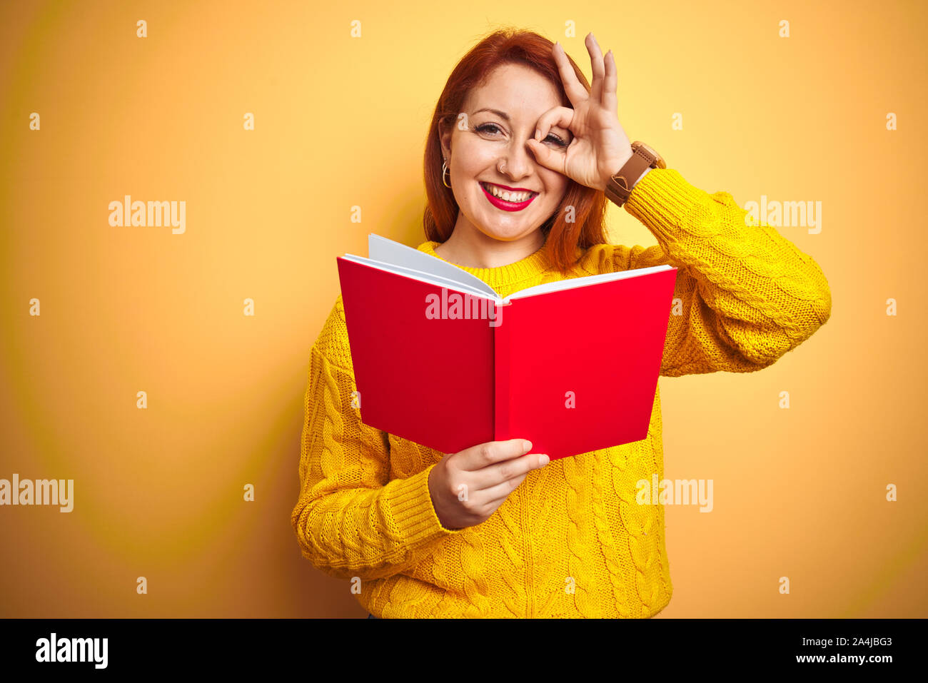 Young redhead teacher woman reading red book over yellow isolated ...