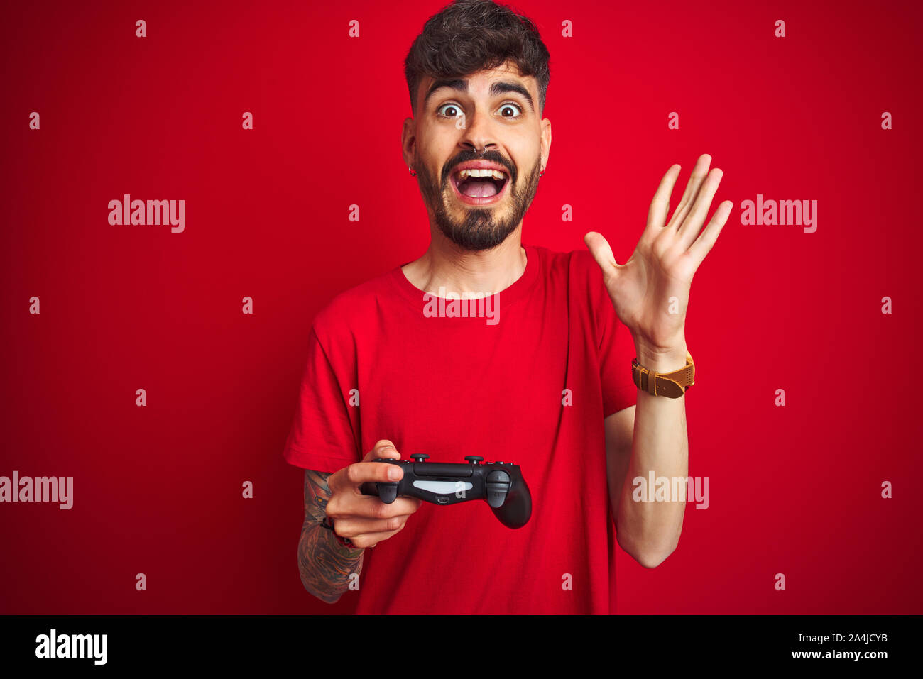 Young gamer man with tattoo playing video game standing over isolated ...