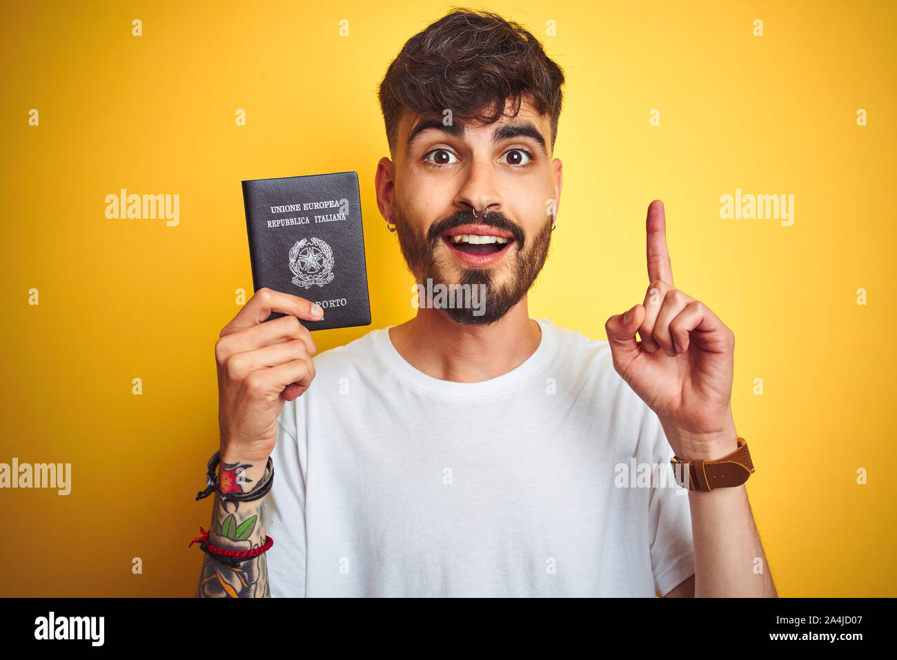 Young man with tattoo wearing Italy Italian passport over isolated ...