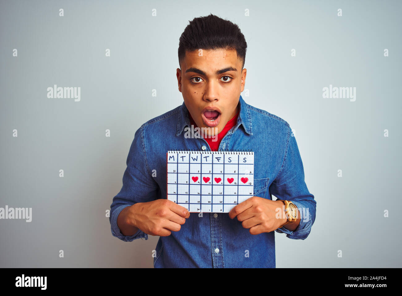 Young brazilian man holding calendar standing over isolated white ...