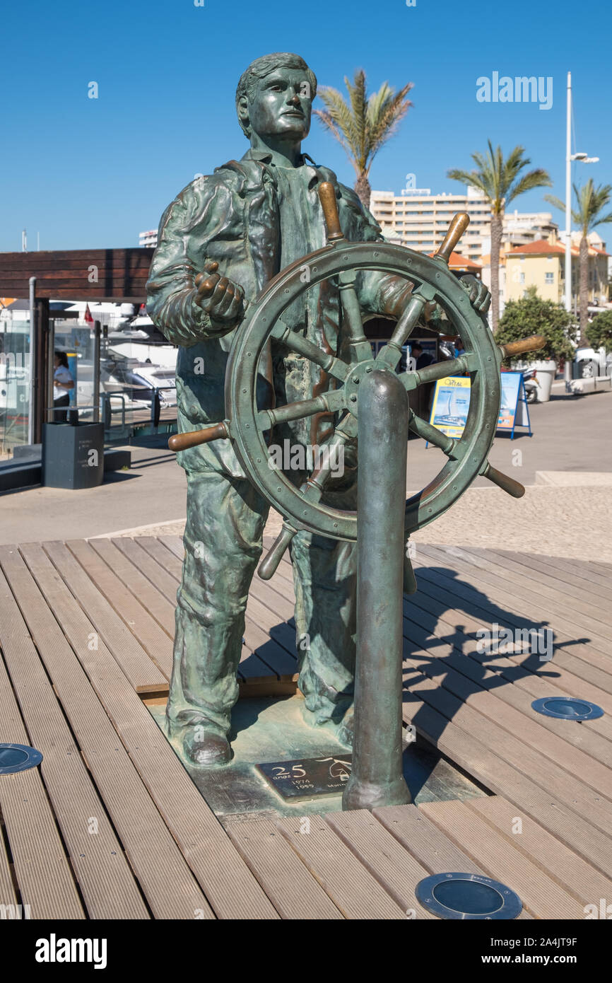 Bronze statue of man steering a boat at the marina at Vilamoura in the ...