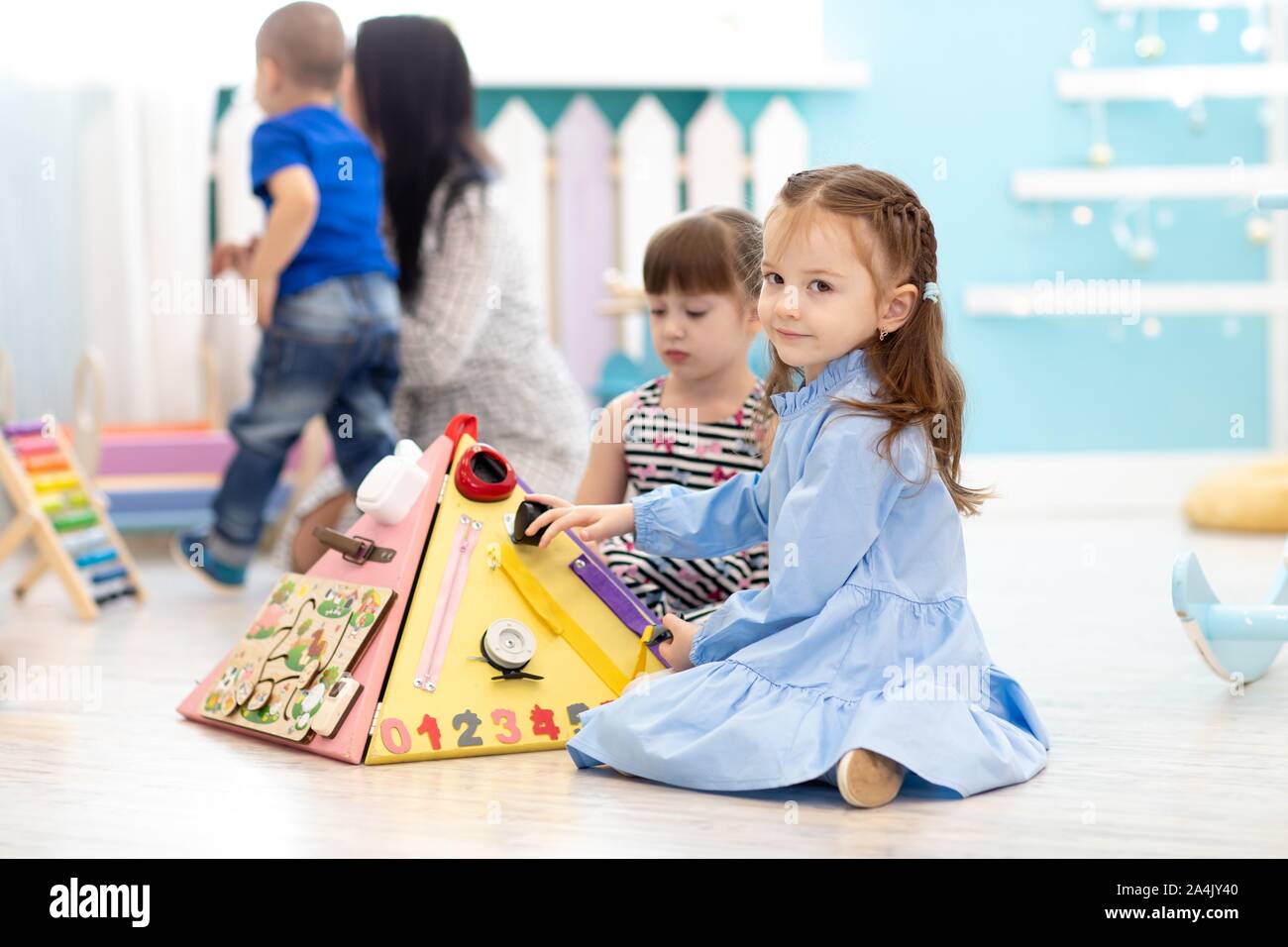 Cute toddler kid girl playing with busyboard in daycare. Children's educational toys Stock Photo ...