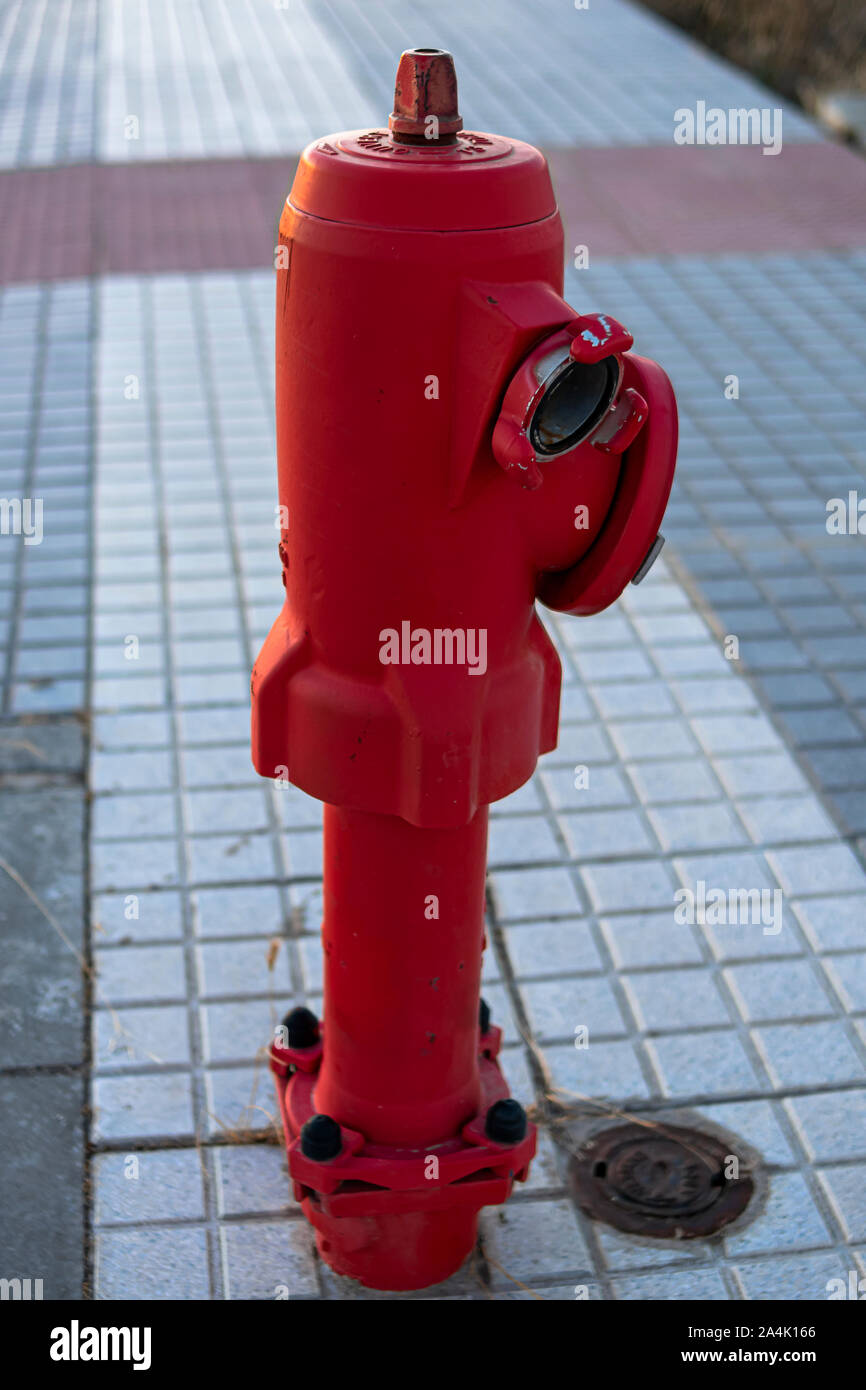 red fire hydrant installed on a city sidewalk Stock Photo - Alamy