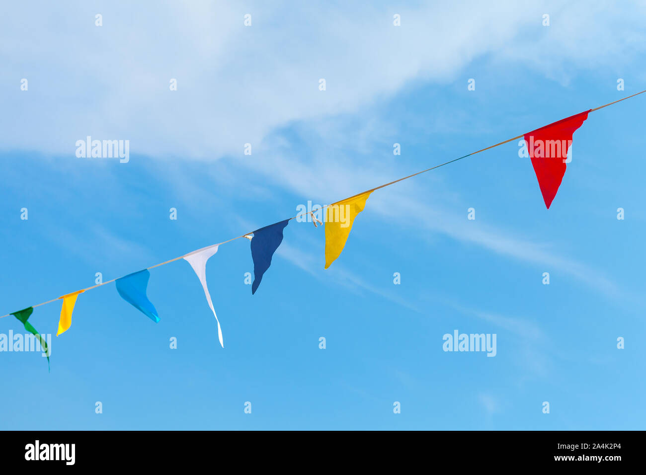 Colorful triangle flags hanging on rope over blue cloudy sky background ...