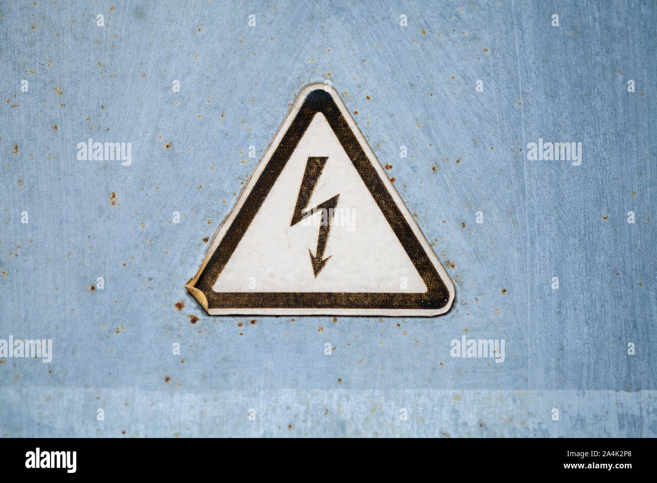 High voltage warning triangle sign mounted on grungy gray metal wall ...