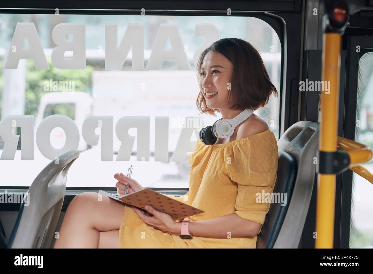Beautiful young woman sitting in city bus and writing some notes in ...