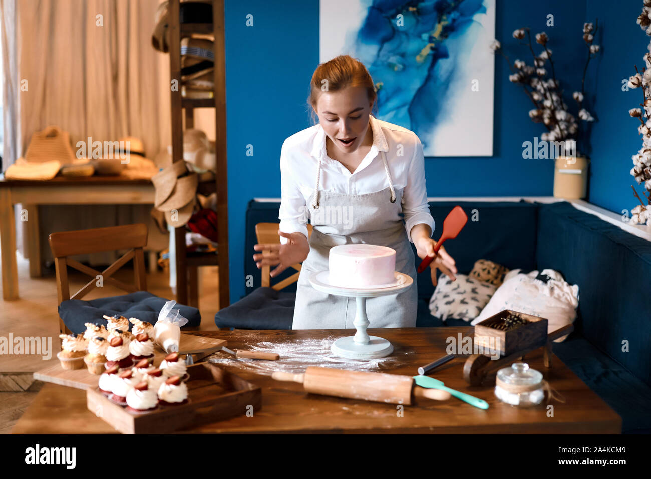 young beautiful cook with wide open mouth staring at cake, being ...