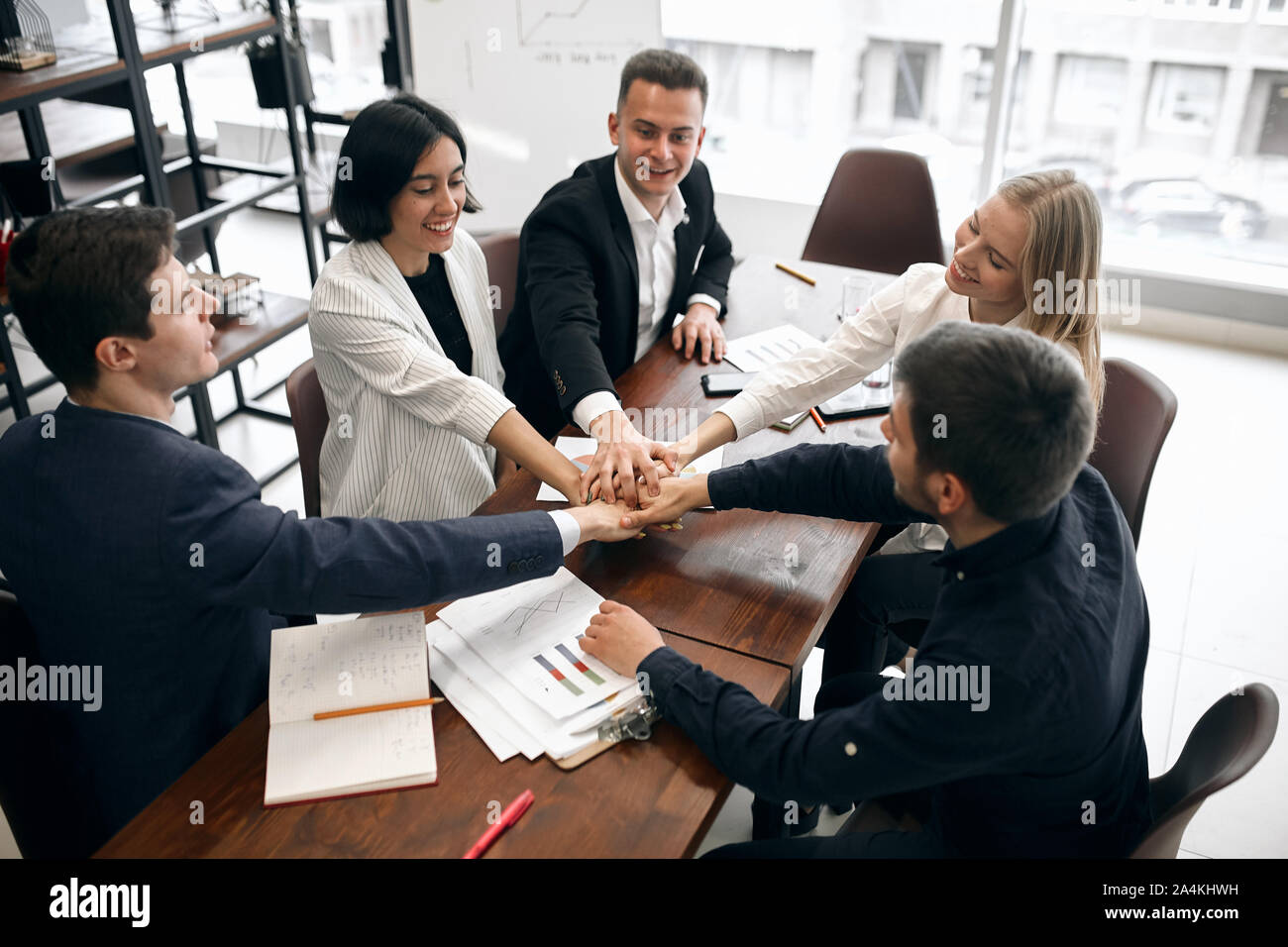 happy cheerful co-workers keeping hands together, close up photo ...