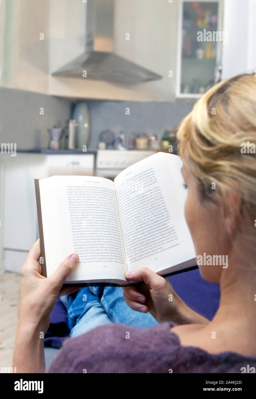 A woman sitting reading in the kitchen Stock Photo - Alamy