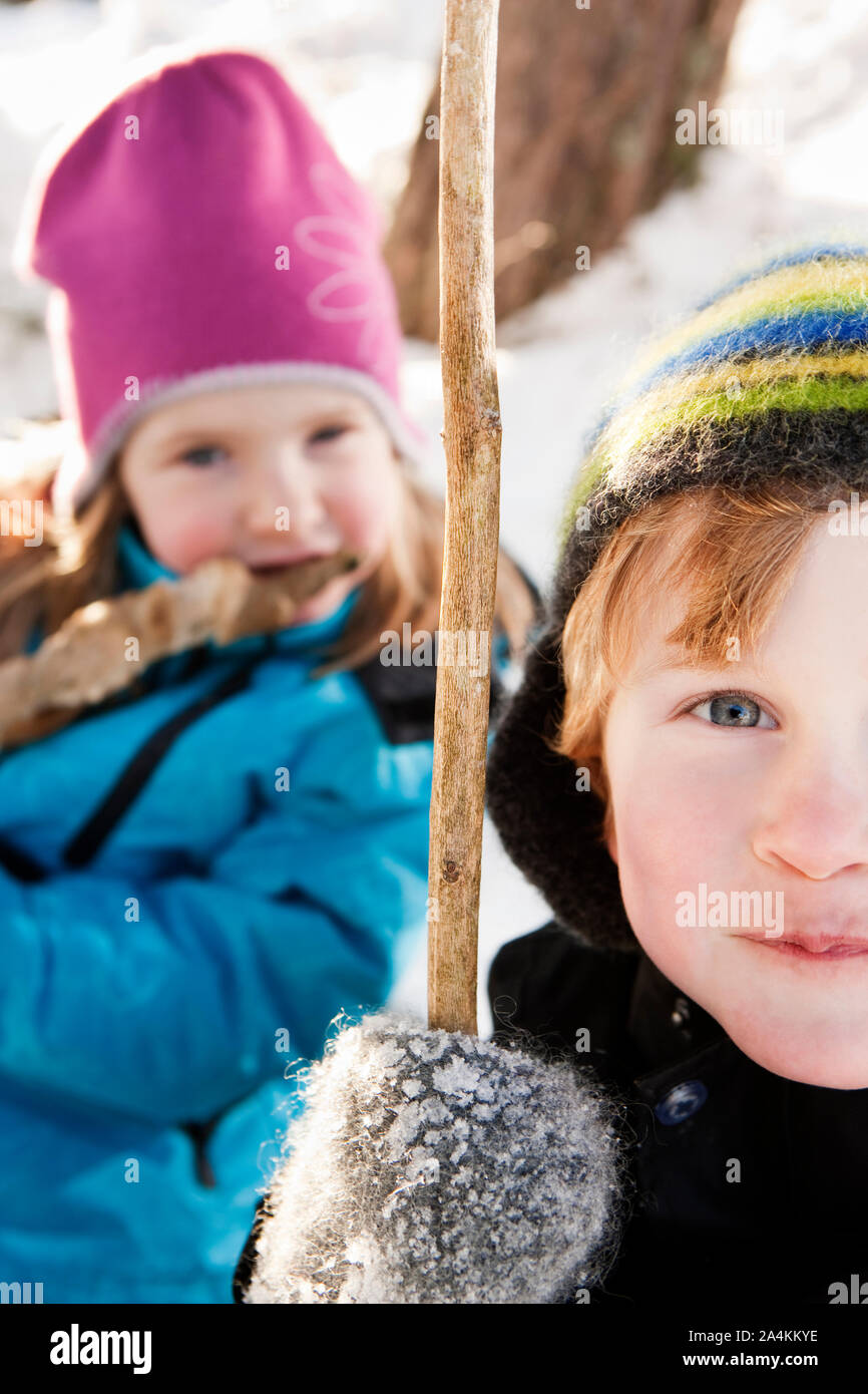 Close-up of child holding Stick and Girl eating food in Background ...
