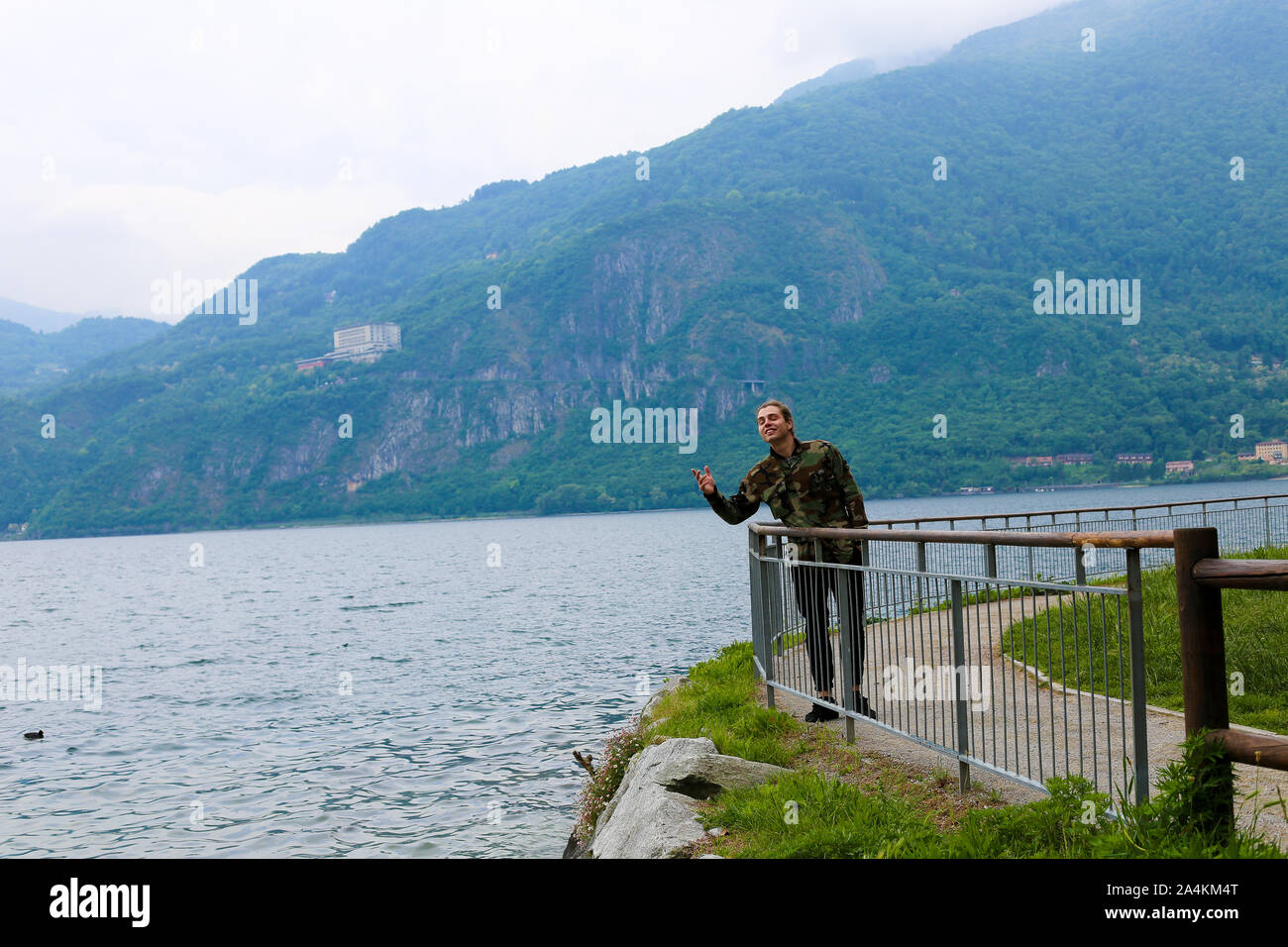 Caucasian tourist standing near banister, lake Como and Alps mountain ...