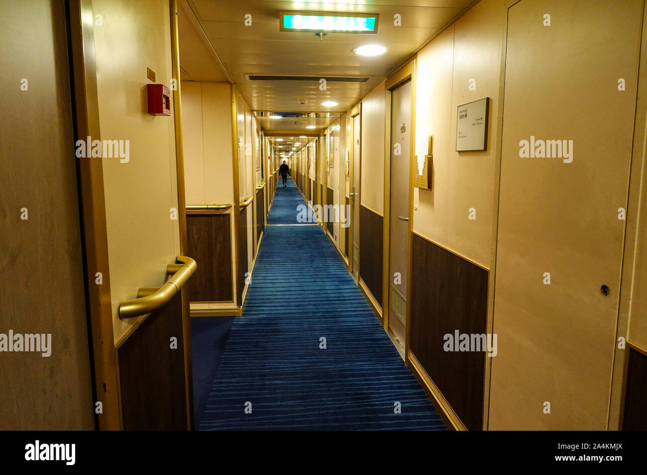 A hallway on a cruise ship with blue carpet and cream colored walls ...