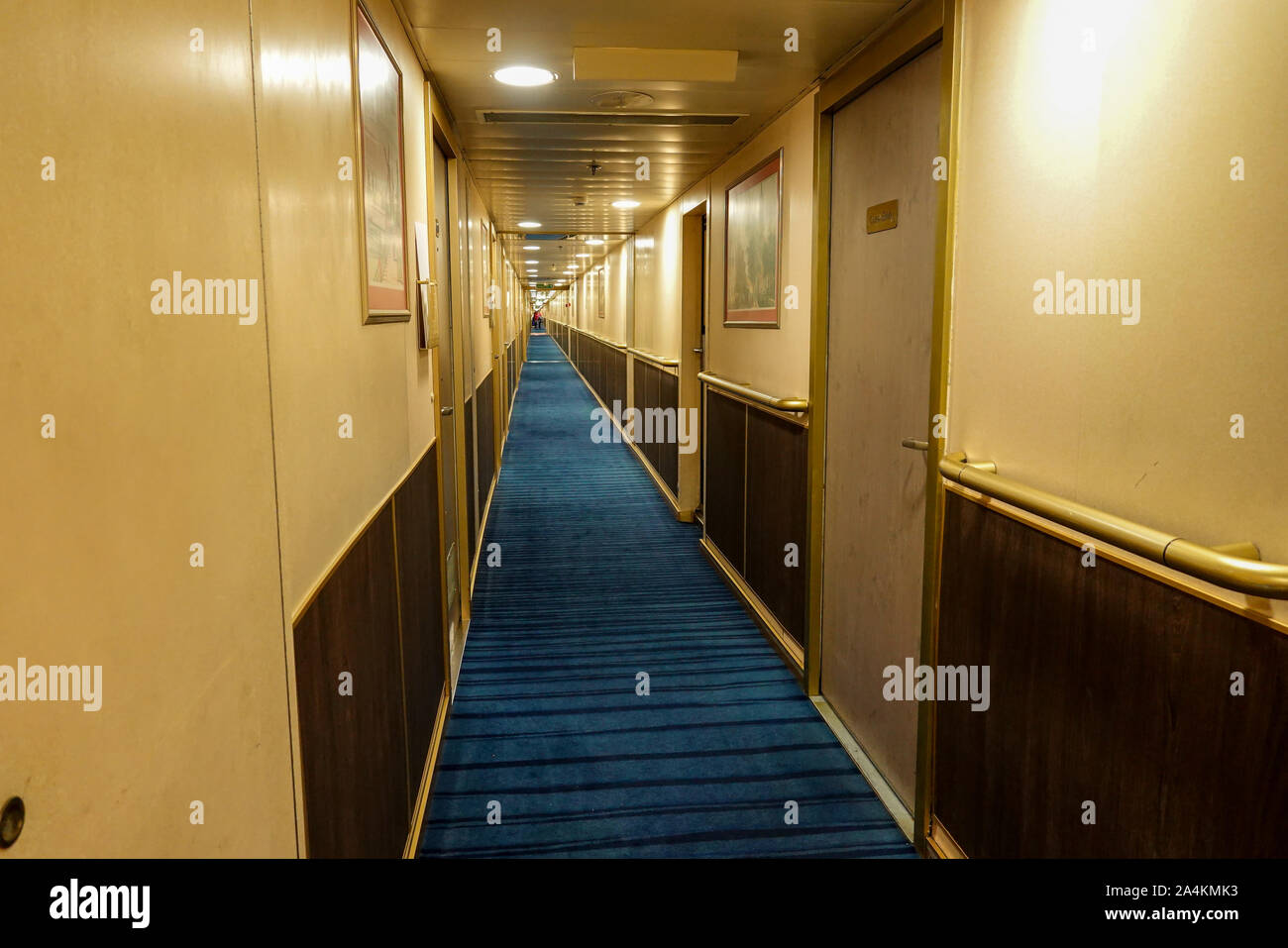 A hallway on a cruise ship with blue carpet and cream colored walls ...