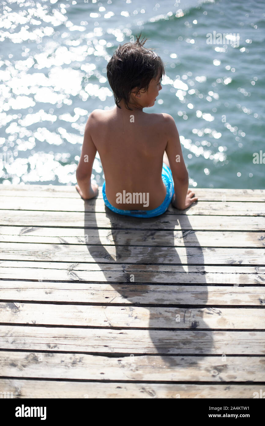 Boy sitting on pier Stock Photo - Alamy