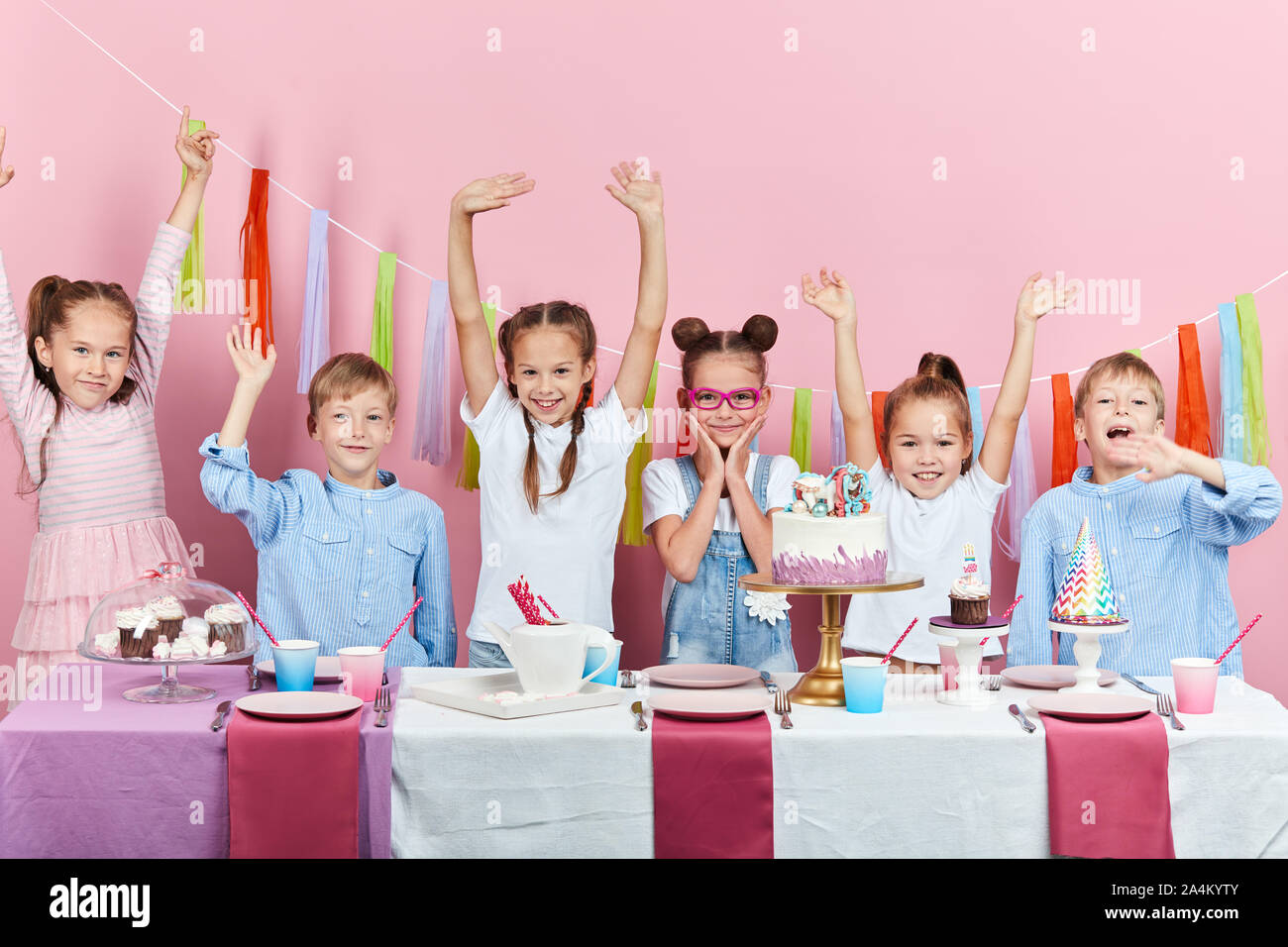 cheerful little boys and girls celebrating birthday, isolated pink ...