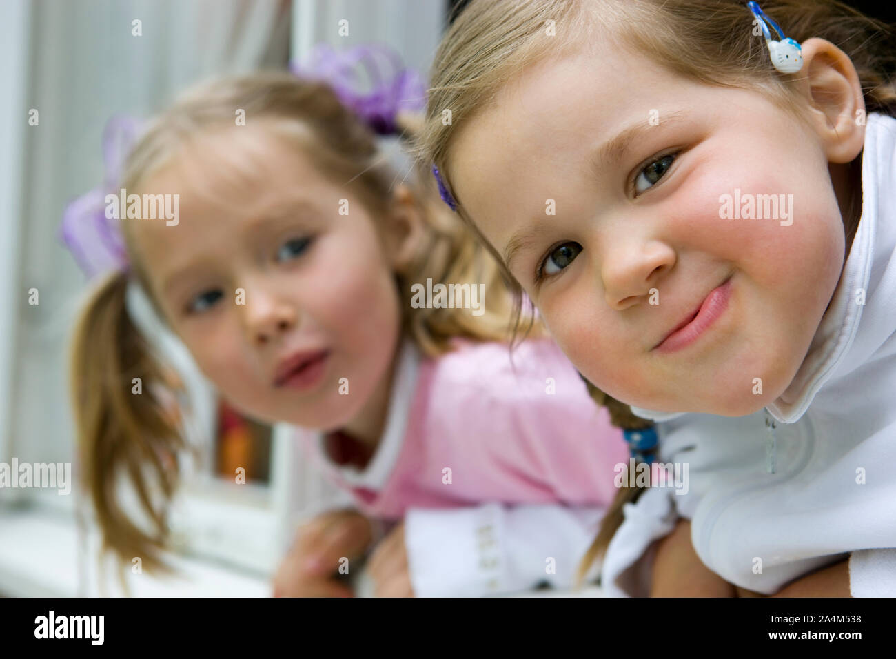 Girls leaning out window making faces Stock Photo - Alamy