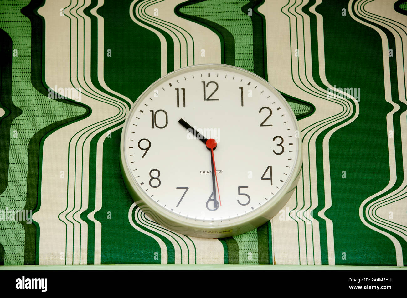 Clock on green wallpaper Stock Photo - Alamy
