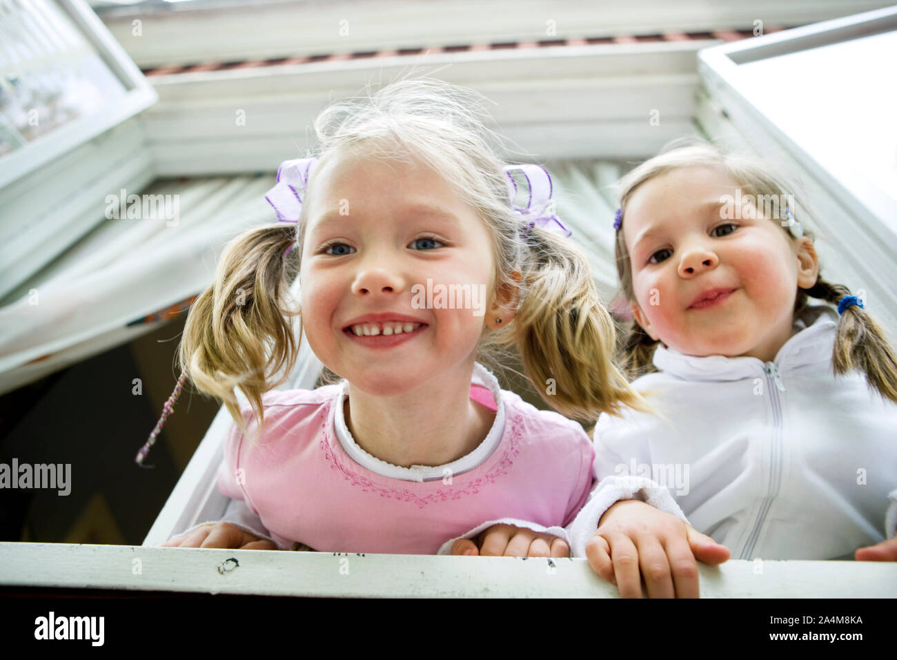 Girls leaning out window Stock Photo - Alamy