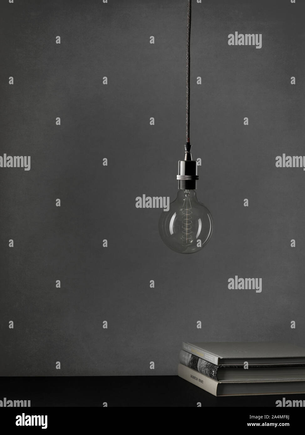 Light bulb hanging against grey background Stock Photo - Alamy