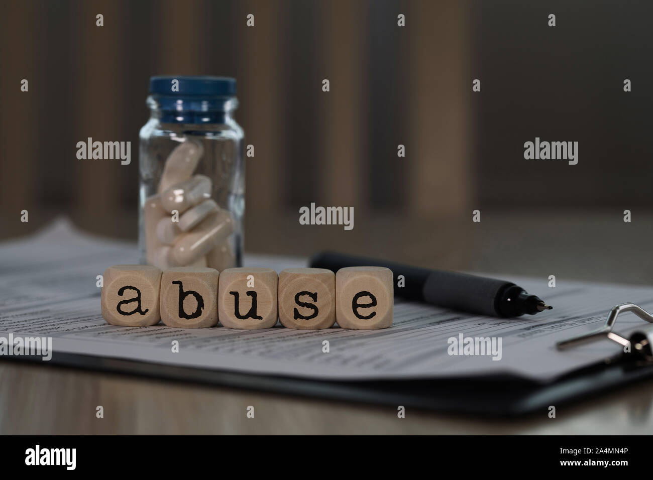 Word ABUSE composed of wooden dices. Pills, documents and a pen in the ...