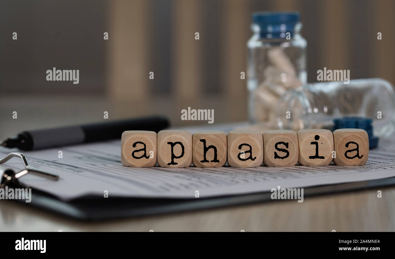 Word APHASIA composed of wooden dices. Pills, documents and a pen in ...