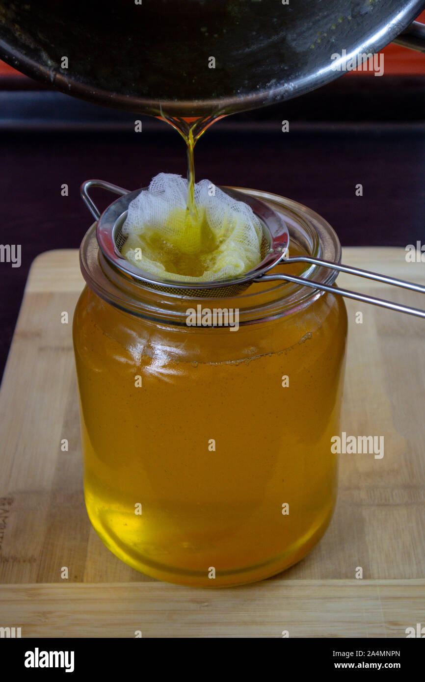 Clarification of butter. Pouring clarified butter into a jar through a ...